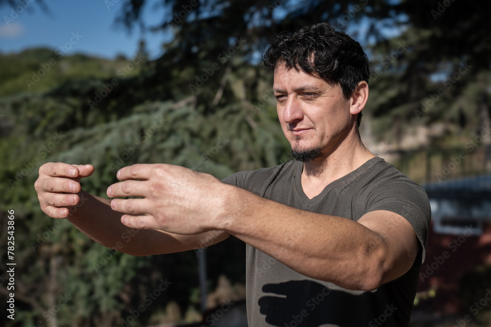A Caucasian man adopts the Tree Hugging Posture during his Qi Gong ...