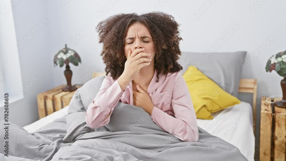A young hispanic woman with curly hair appears ill, sneezing and ...