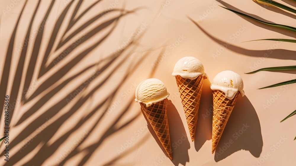 Three vanilla ice cream cones with palm shadow on a warm beige surface ...