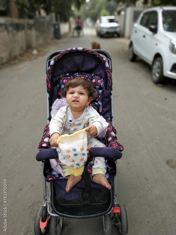 Cute little baby boy is sitting on the stroller in the middle of the ...