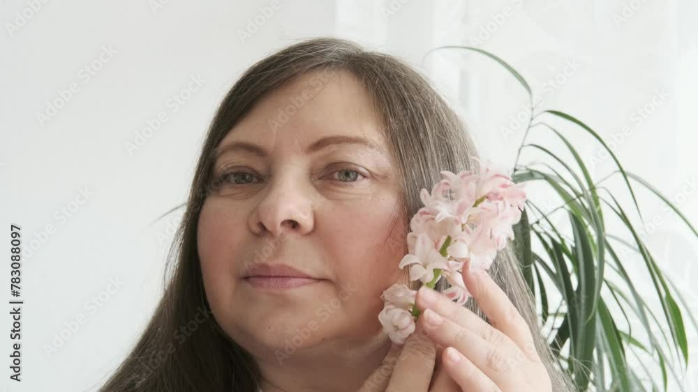 Vidéo Stock aging woman with hyacinth flower looks herself in mirror ...
