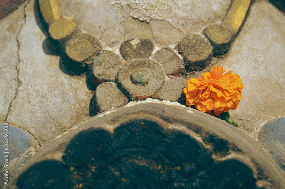 A vibrant orange marigold flower placed on a stupa as a sacred Buddhist ...