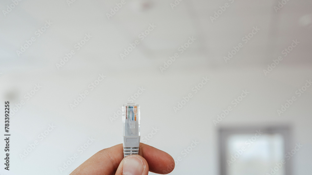 LAN ethernet cable in hand. Gray RJ45 twisted pair cable for computer ...