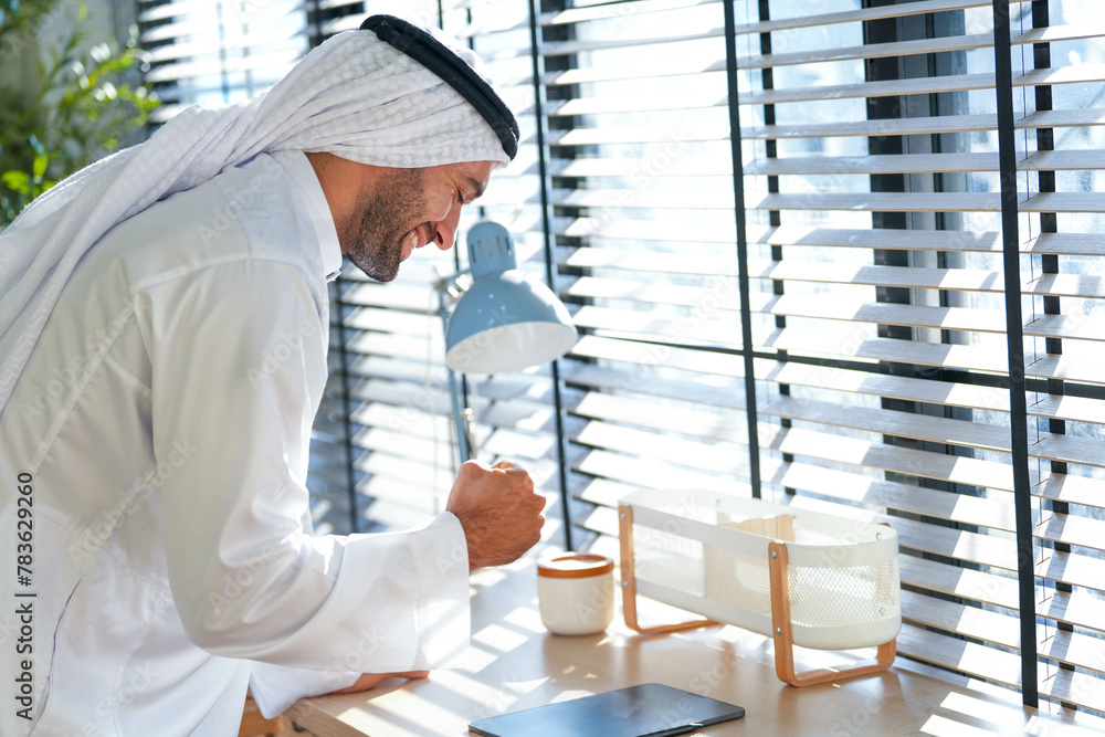 Profile of a smiling man in traditional Emirati attire, his face lit by ...