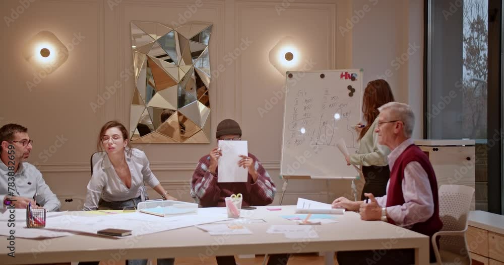 A multi-generational, mixed-race business team gathers in a meeting ...