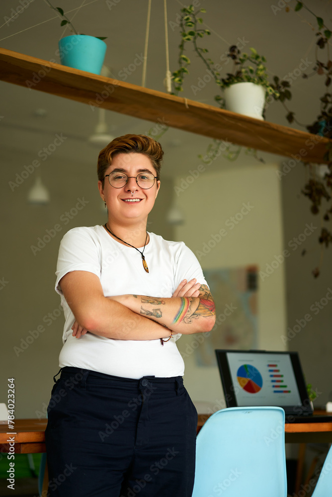 Transgender pro in modern office smiles confidently, crossed arms ...