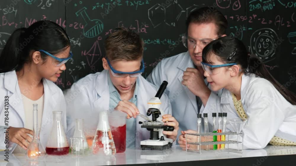 Multicultural student looking under microscope while cute girl inspect ...