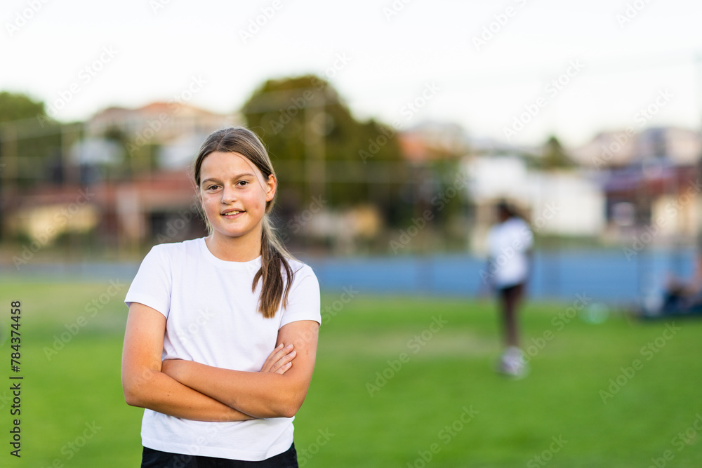 one tween girl standing looking at camera with another child blurred in ...