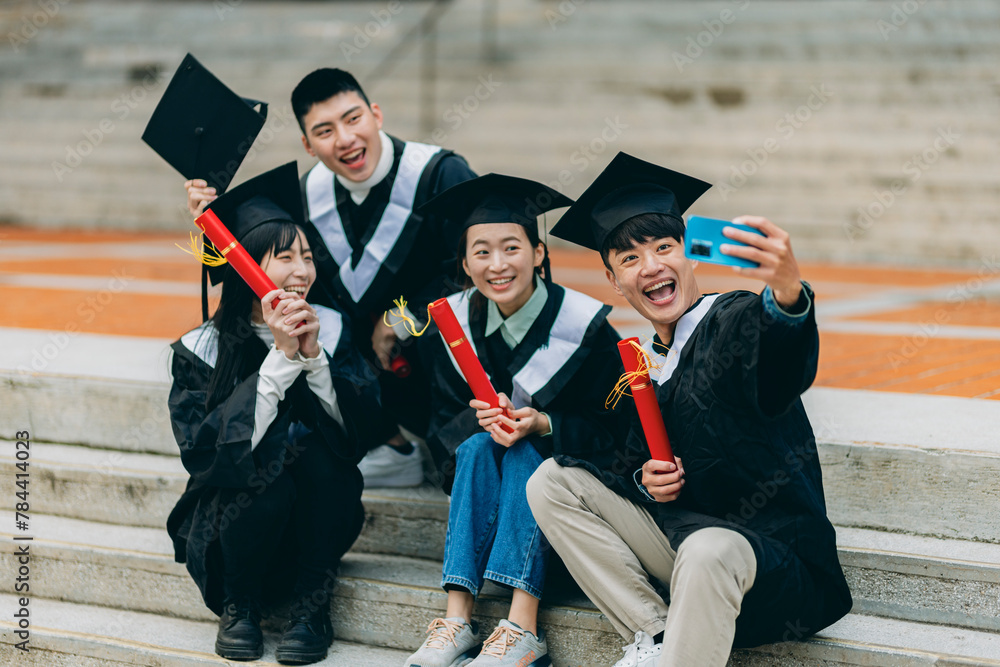 Foto de Asian university students, clad in graduation gowns, use ...