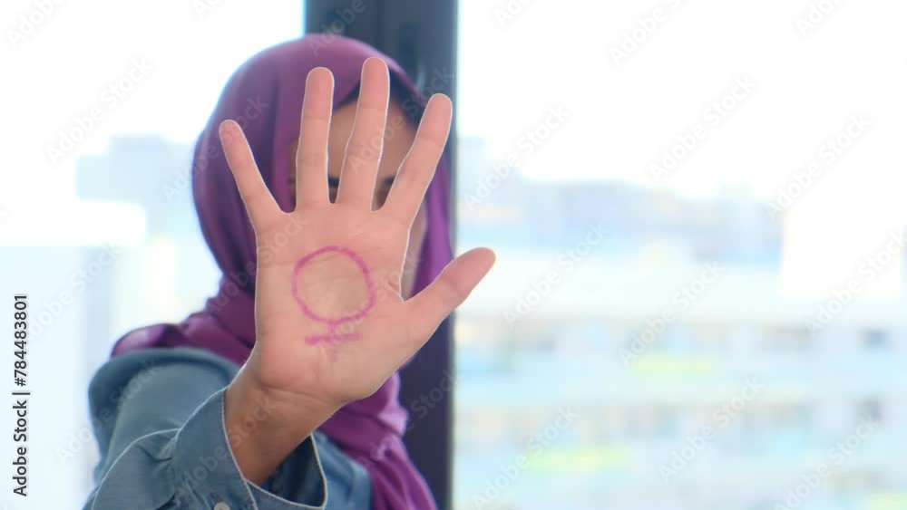 Woman with purple hijab and woman symbol on the palm of her hand looks ...