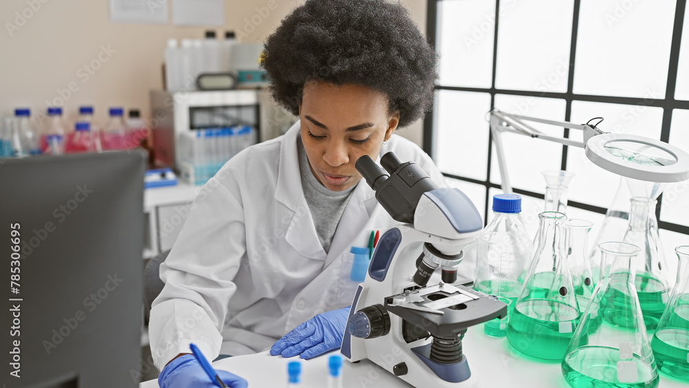 African american woman scientist examining sample in laboratory with ...