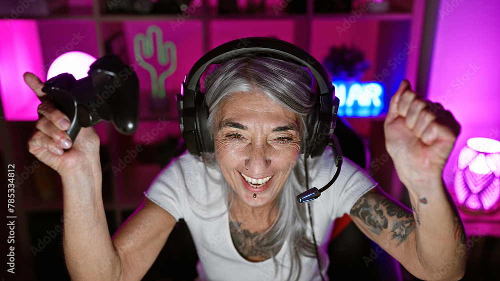 Confident grey-haired middle-aged woman streamer celebrating a big win ...