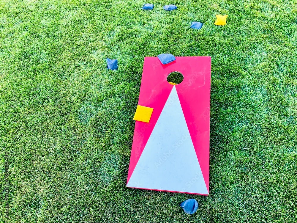 Red and white cornhole board with bean bags on lawn in summer, leisure ...