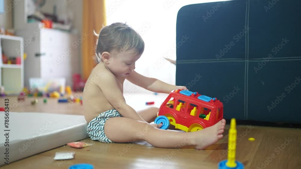 baby child playing toy car bus on the floor in kindergarten. happy ...