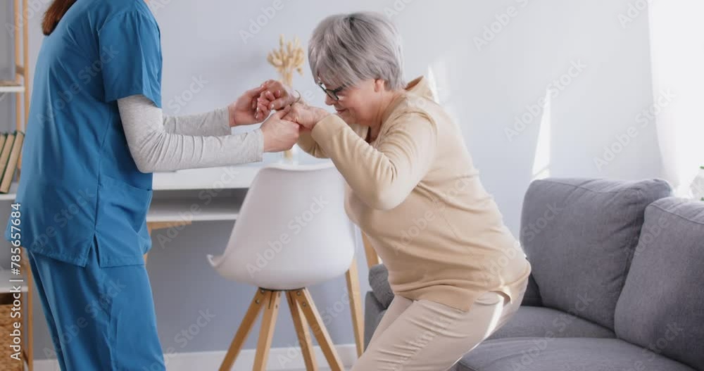 Caregiver helps a senior woman patient walk during home rehabilitation ...
