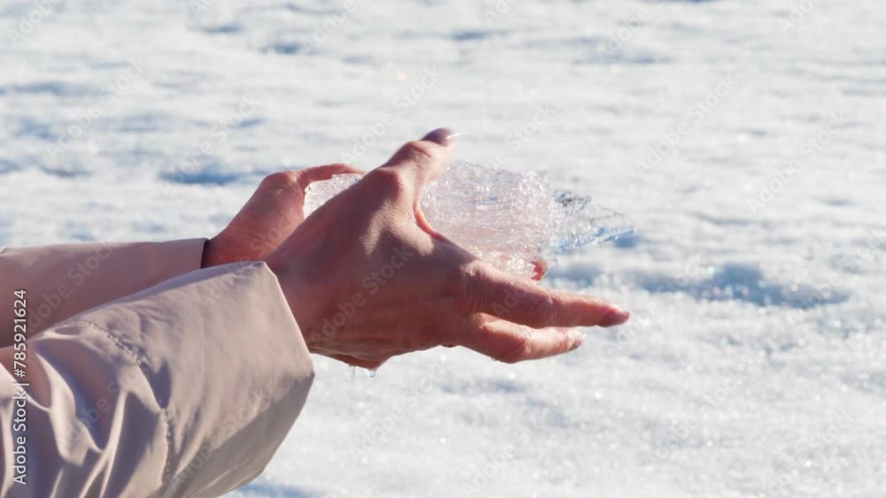 Close-up of female hands holding melting ice crystals. The ice melts in ...