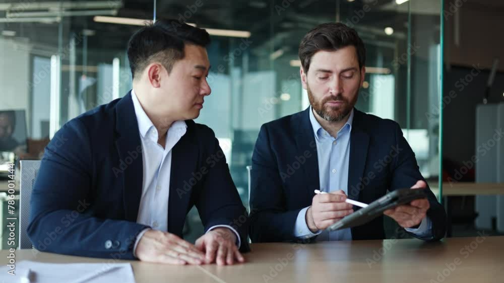 Japanese boss checking creative project on device display and listening ...