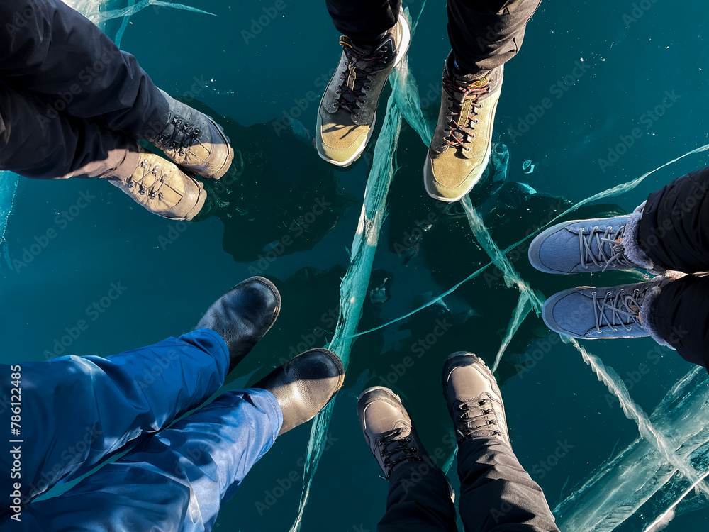 Fragile thin brittle ice underfoot. Male and female feet on ice. Cracks ...