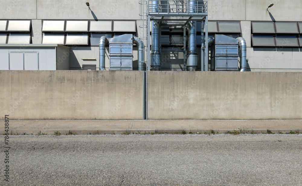 Concrete surrounding wall with factory machineries and windows on ...
