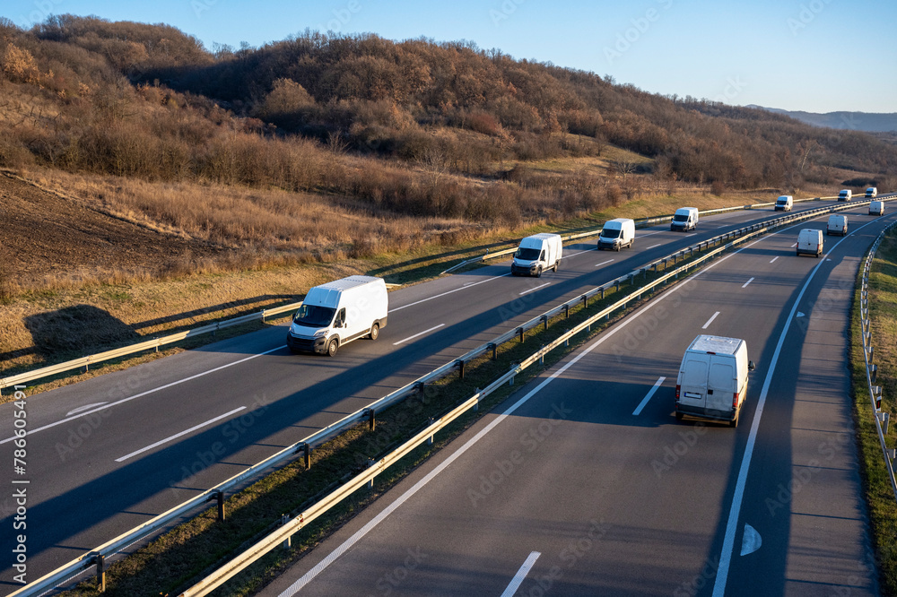 Eleven white minivans are moving in a convoy on the highway. White ...