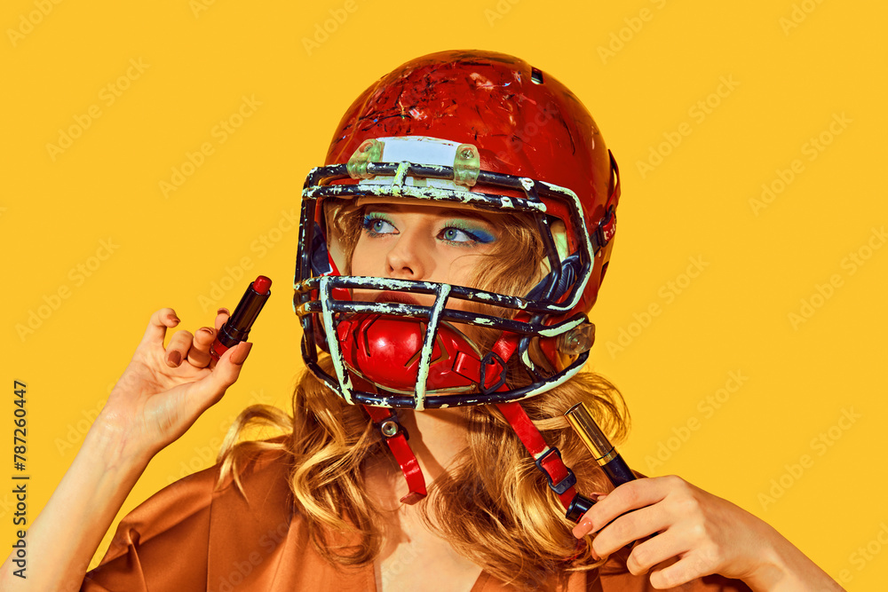 Portrait of woman in elegant attire wearing football helmet makes ...