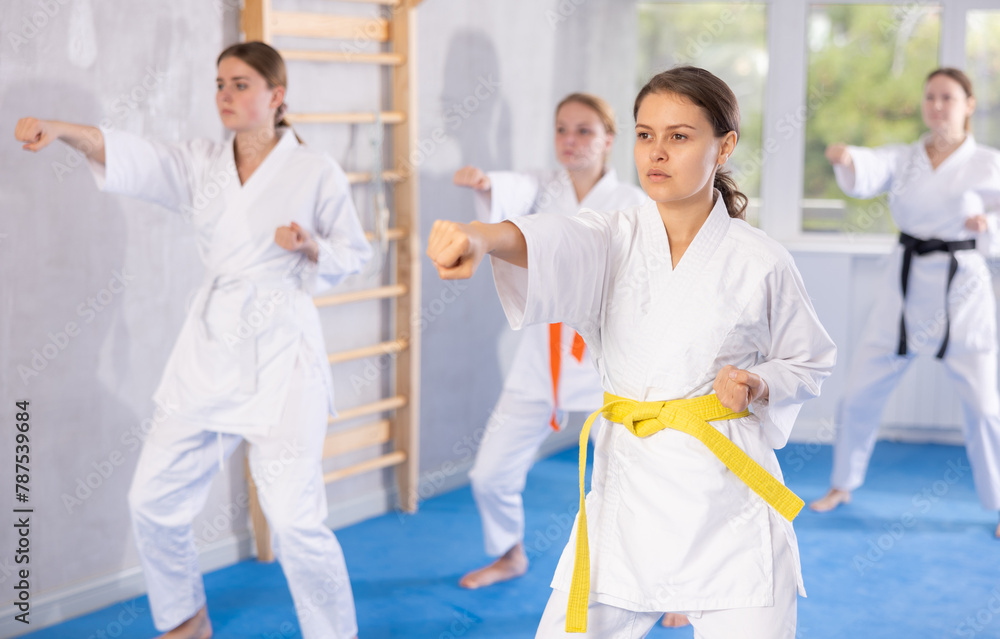 Motivated Sporty Teenage Girl With Group Of Young Female Karate Practitioners Wearing White