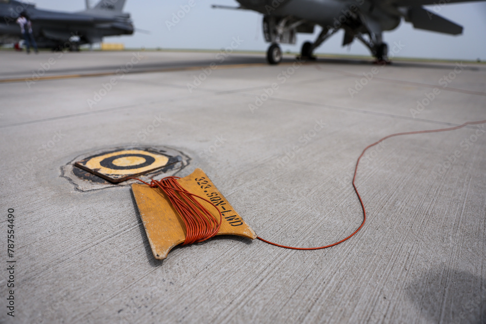 Electrical grounding cables are seen on a runway. Military fighter ...