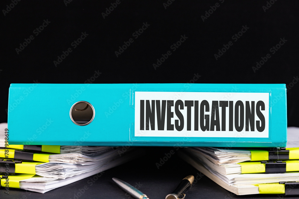 INVESTIGATIONS text is written on a folder lying on a stack of papers ...