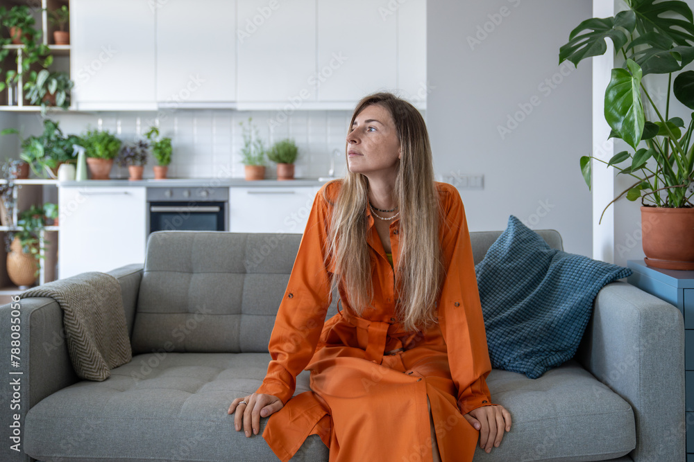 Tired woman in tension sitting on sofa indifferent looks aside trying ...
