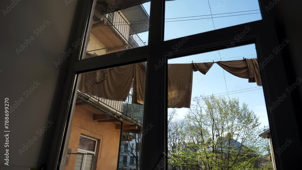 A view through the window dark room at laundry hanging on clotheslines on the outside in the ...