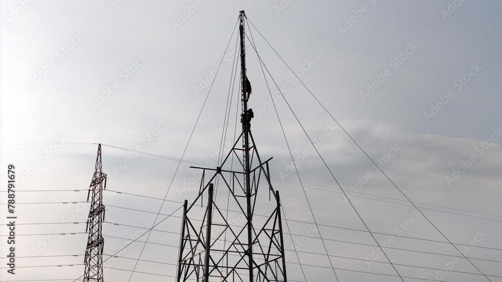 construction of electric pylons. people climbing power towers to erect ...