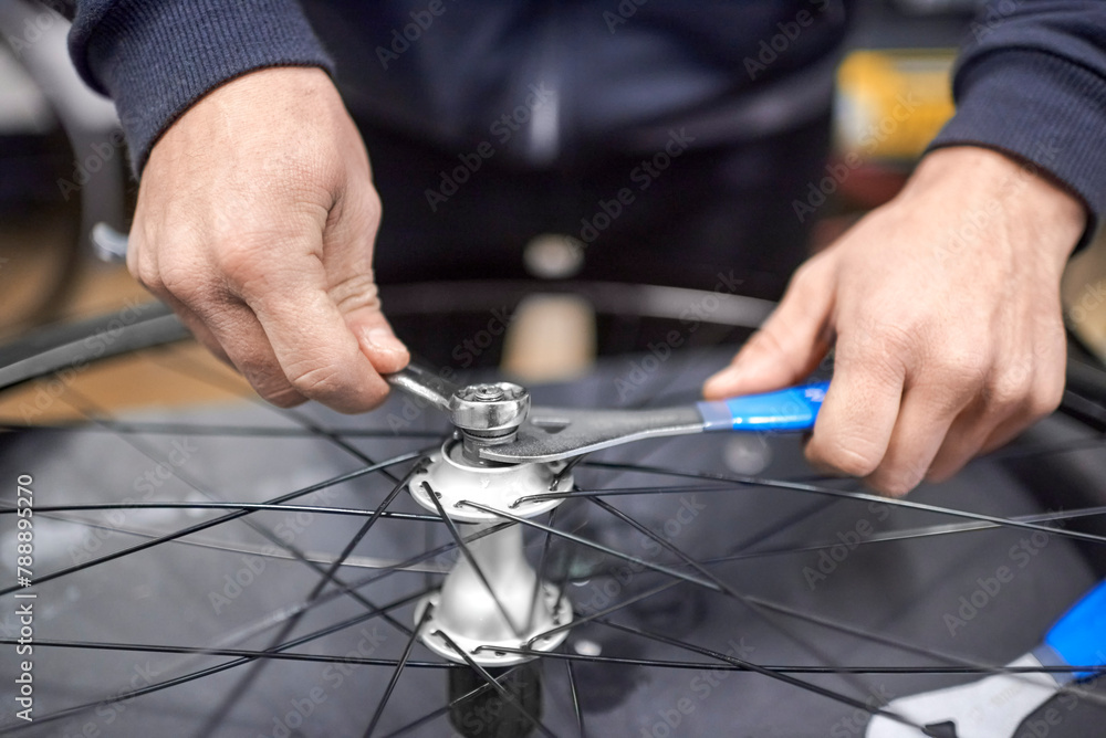 Unrecognizable person assembling a bike wheel axle after disassembling ...