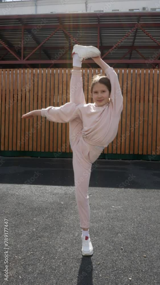 Vertical format. A girl gymnast in sportswear demonstrates an element ...