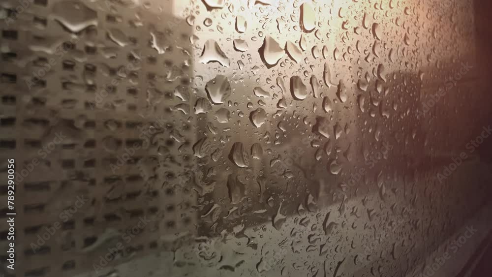 Rain falling on window in skyscraper apartment. Dark and stormy rainy day in big city life. View ...