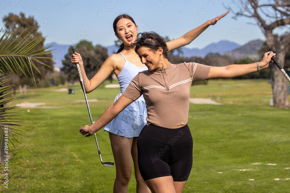 Two friends together on the golf course for a game. The female golfers ...