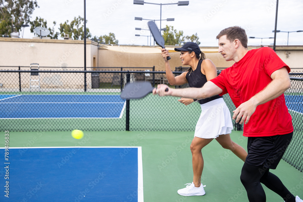 Pickleball coach giving a lesson to a student on an outdoor court. The ...