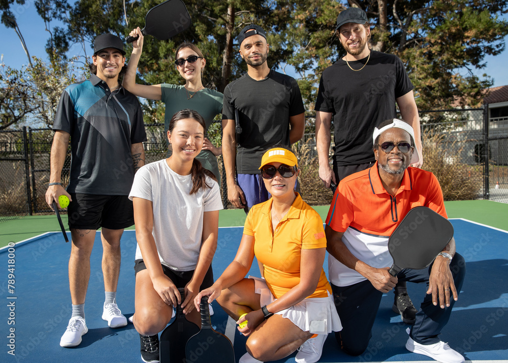 Group of seven friends together on pickleball court. The diverse ...