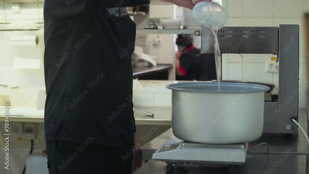 Pouring water from measuring cup in the cooking pot at the restaurant ...