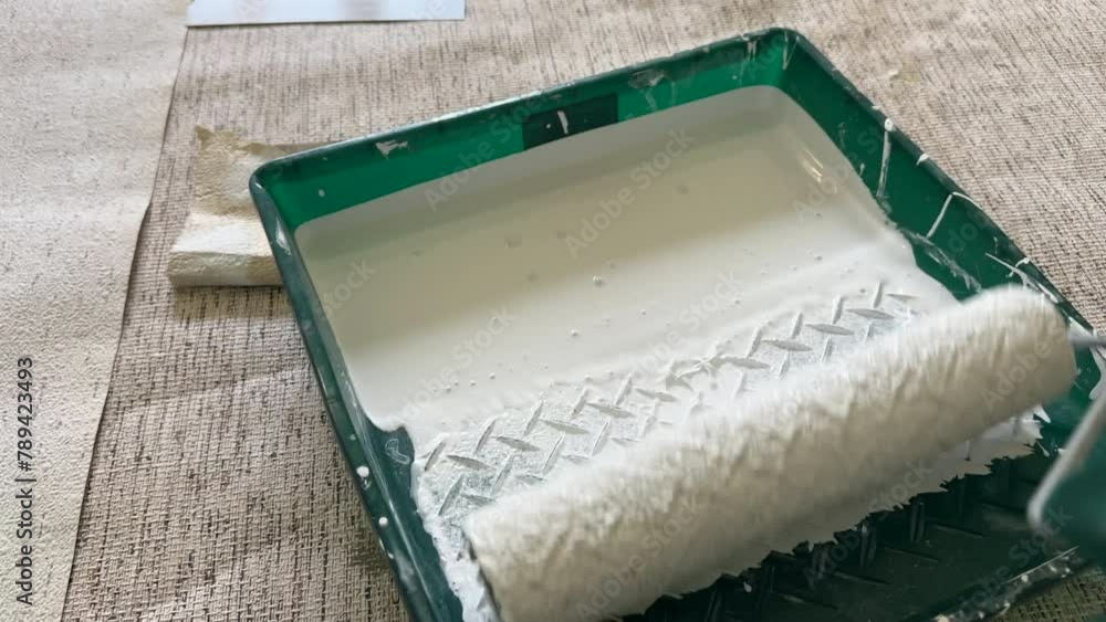 Paint roller with paint in container room. Painting the walls in a room ...