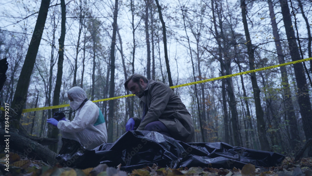 Detective examines the body of a victim of a maniac, with forensic ...