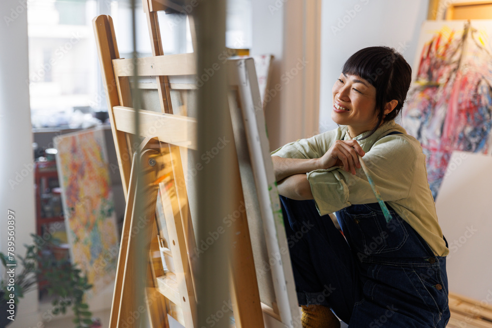 Smiling thoughtful artist looking at beautiful painting on canvas Stock ...