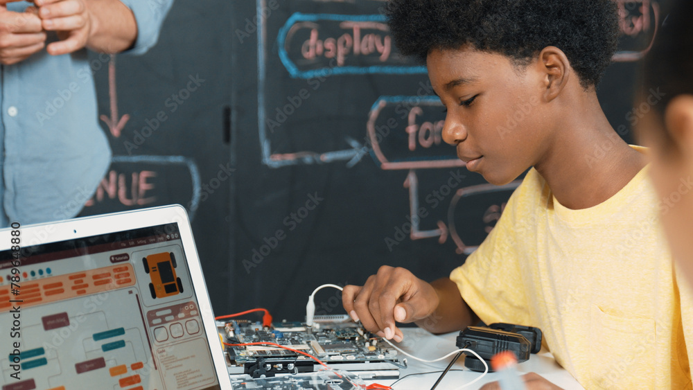 Cute african boy learning to use electronic tool while laptop display ...