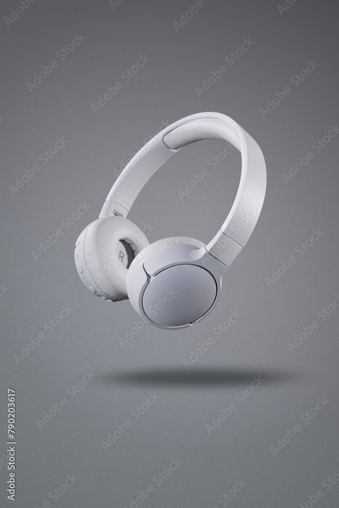 White overhead headphones on a gray background in levitation in the air ...