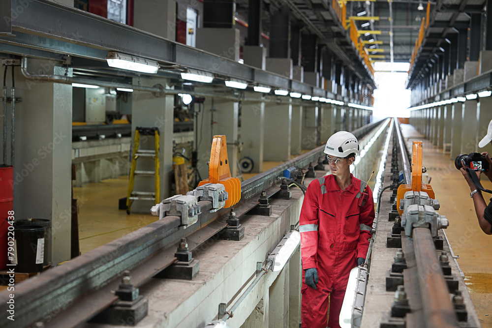 In the electric train maintenance depot, male engineers wearing ...
