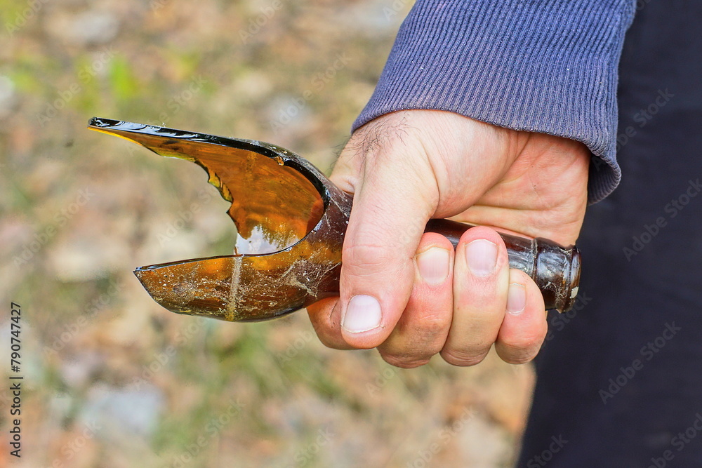a piece of a broken glass dirty bottle of brown color with sharp and ...