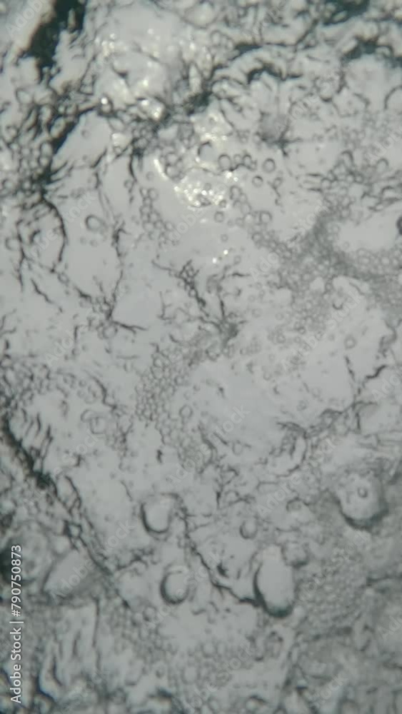 Vertical video, Raindrops falling on water surface, Bottom view ...