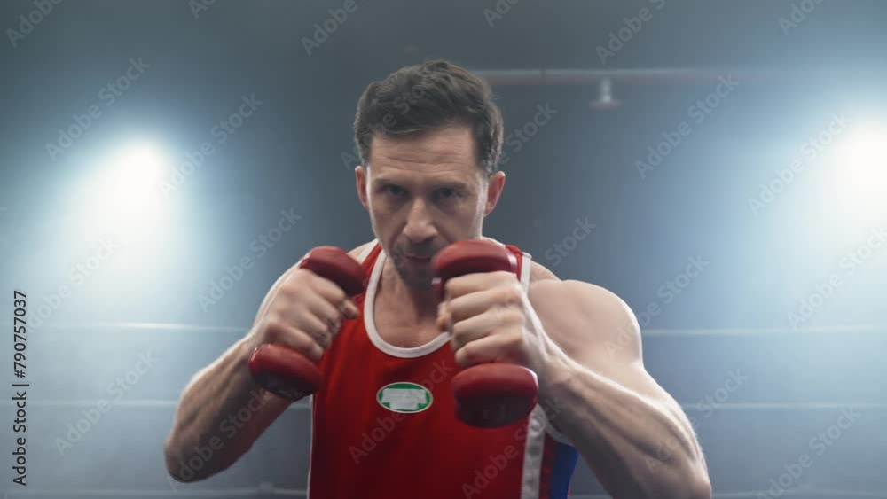Focused boxer fighter training punches with dumbbells in hands looking ...
