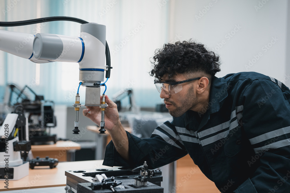 Engineering student assembling a robotic arm using a computer in a ...