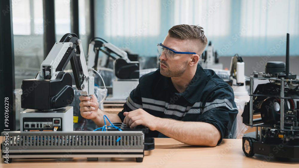 Engineering student assembling a robotic arm using a computer in a ...