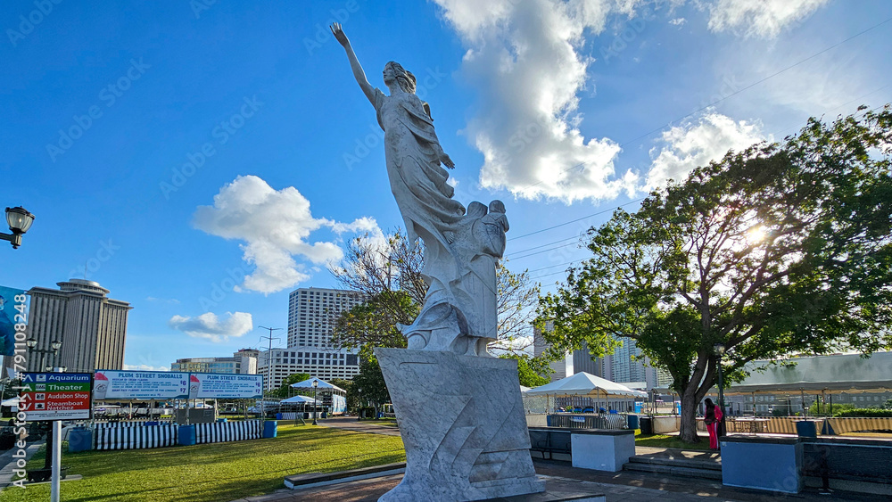 The Monument to the Immigrant, a white stone statue along the riverwalk ...